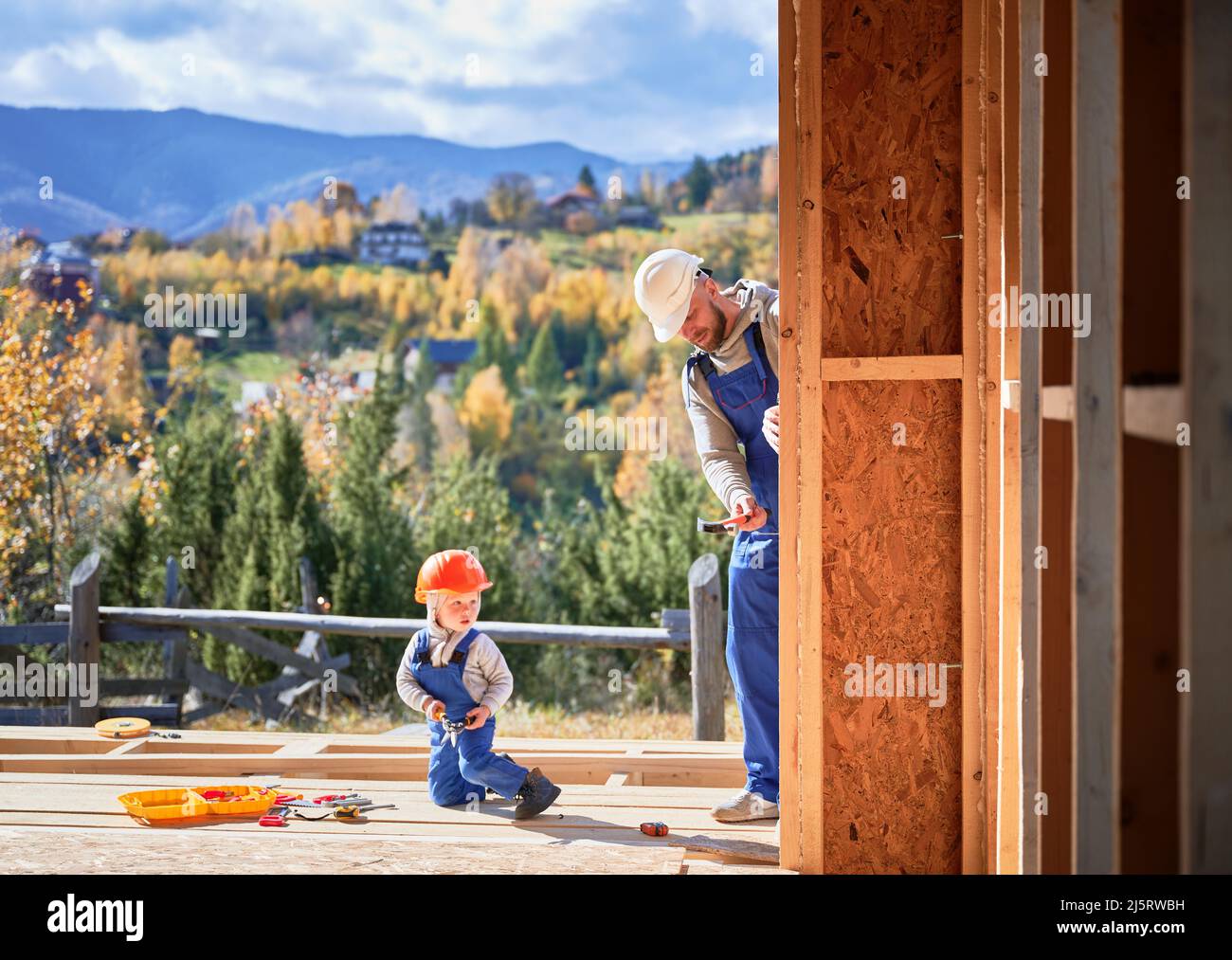 Father with toddler son building wooden frame house. Male builders ...