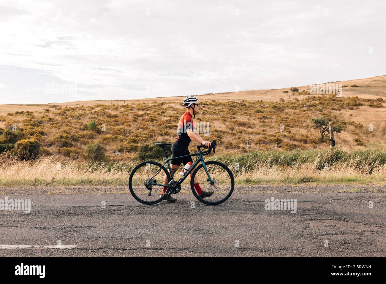 Side view of young professional cyclist walking with her road bike on ...