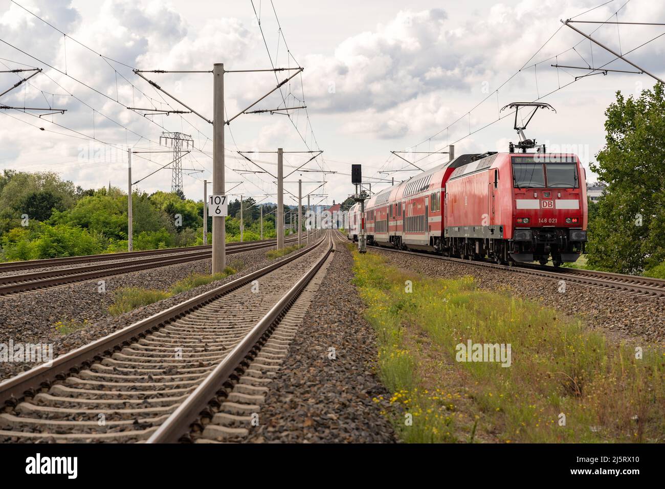 Red train from the Deutsche Bahn company rolling on the railroad to a ...