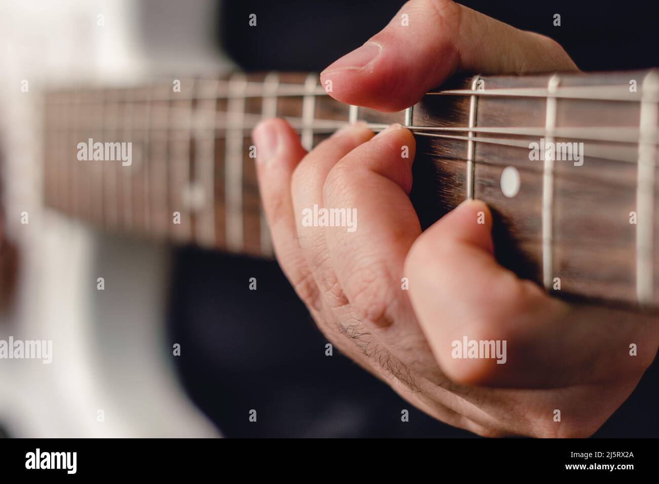 close-up male hand doing bending technique on electric guitar, focus on ...