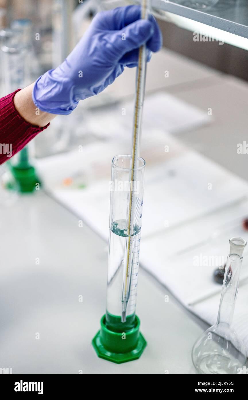Assistant measures temperature of alcohol with thermometer Stock Photo ...