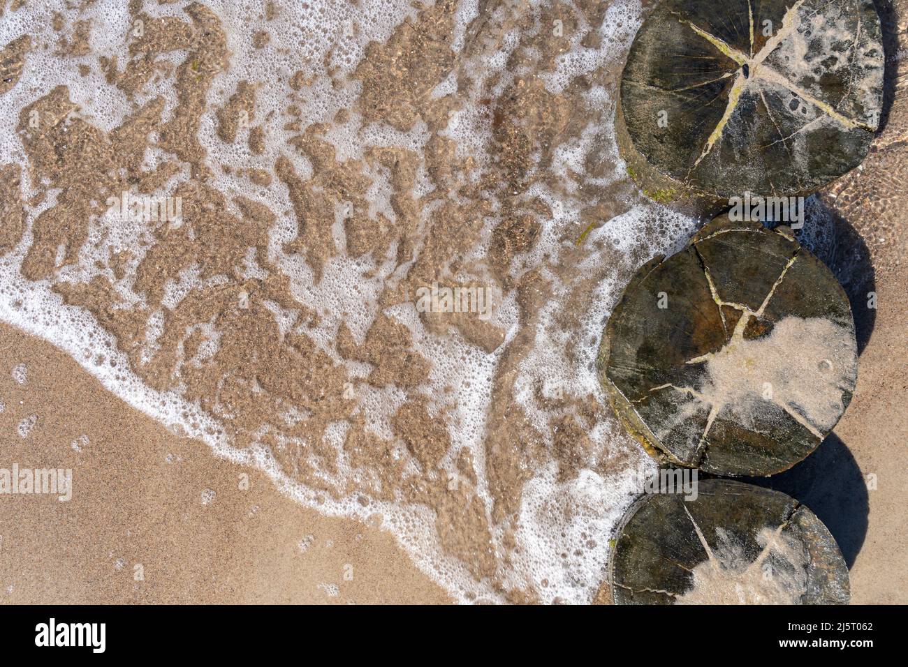 Water from the sea splashing on the sand of a beach. Top down view of ...