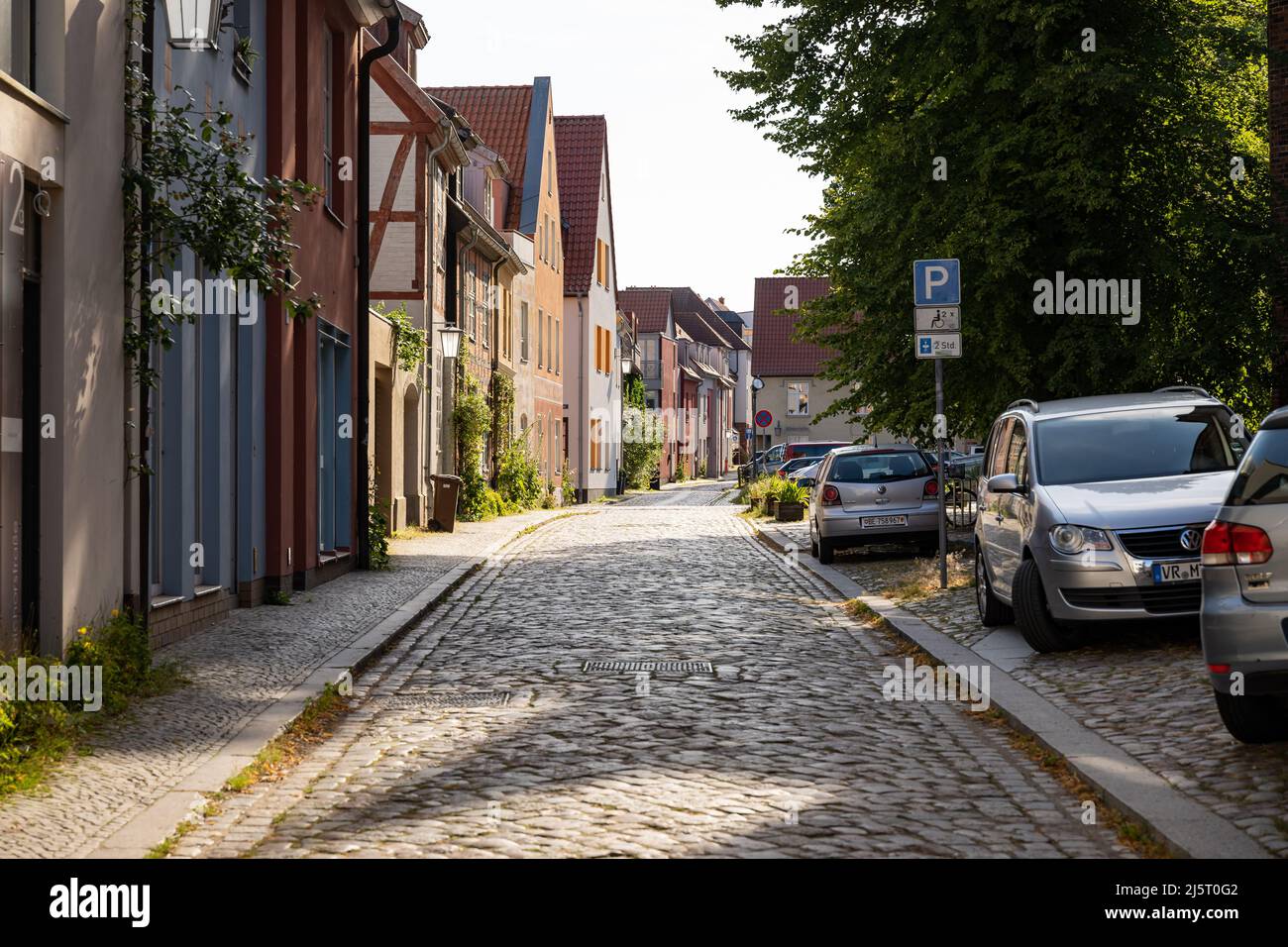 An old street with parking cars on the right side. A summer day in the ...
