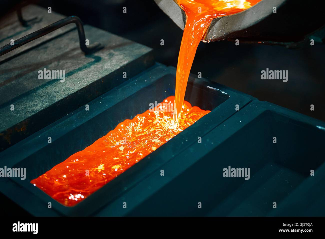 Pouring red molten silver metal into graphite casting form Stock Photo ...