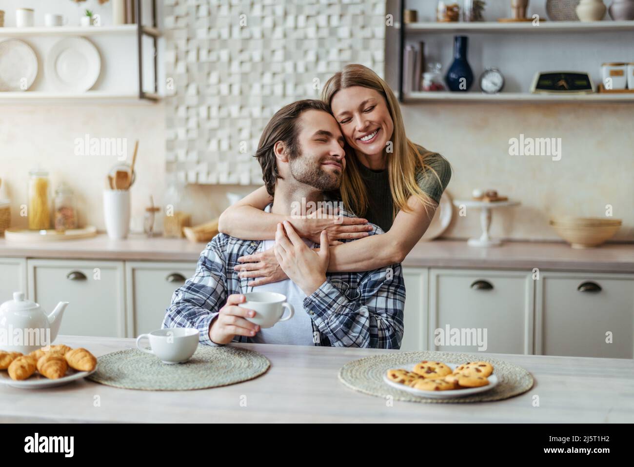 Glad young european lady hugging male with stubble drink coffee, enjoy ...