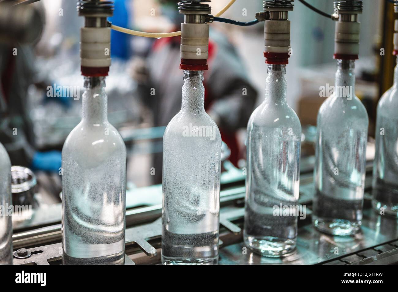 Equipment pours vodka into glass bottles on production line Stock Photo ...