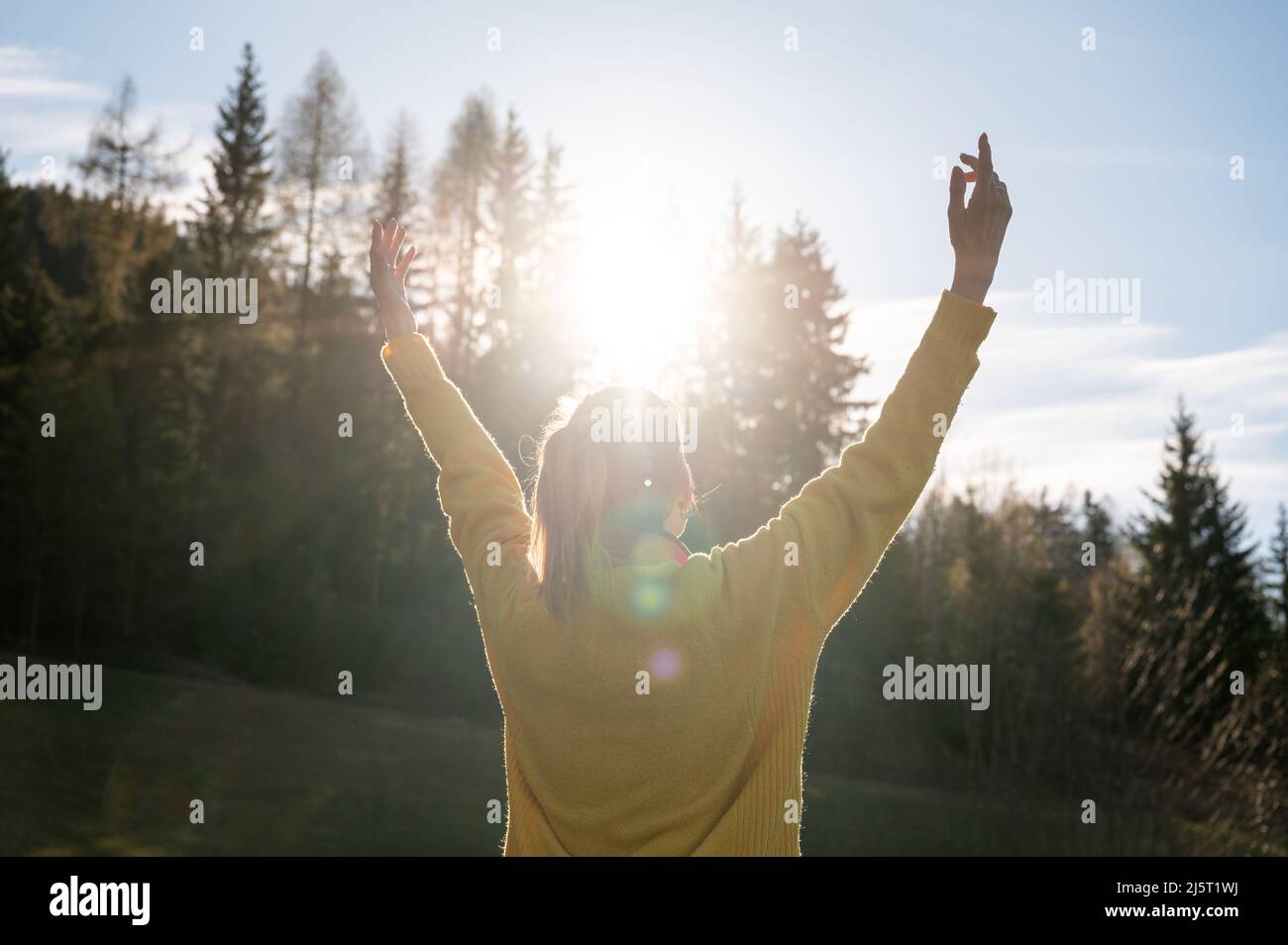 View from behind of a young woman in yellow sweater standing with her ...