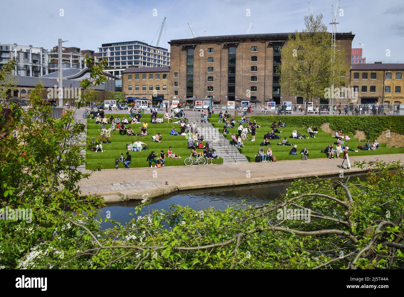 People enjoy the sunshine on the steps at Granary Square in King's ...