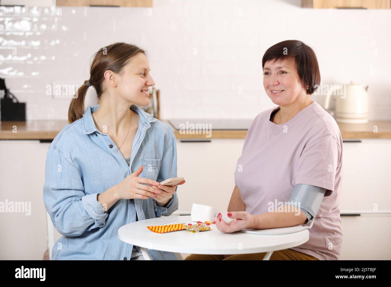 Happy young female providing medical care, helping to support an senior ...