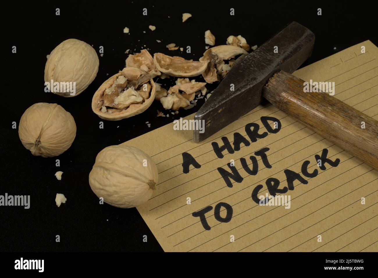 Four walnuts (one of them cracked) and a hammer on a dark scratched ...