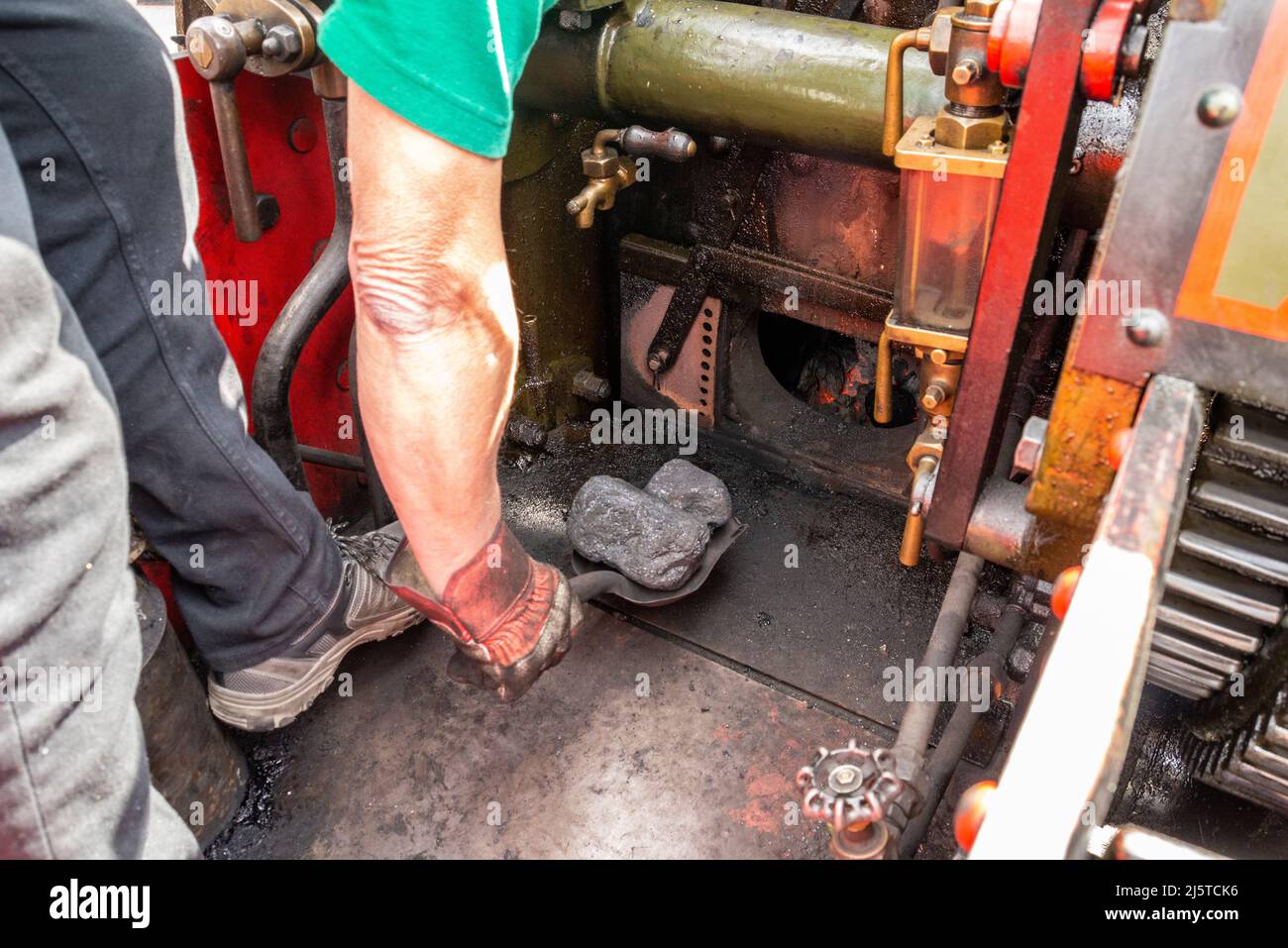 Coal being shovelled into the firebox of a steam traction engine. Welsh ...