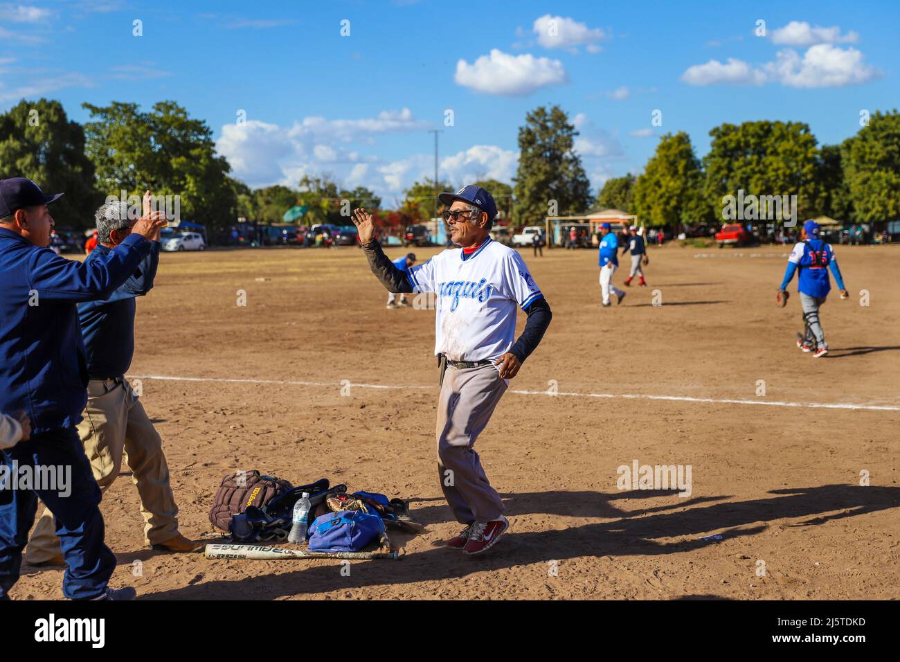 Men watch the llama baseball game on a dirt field. Marte R. Gómez or ...