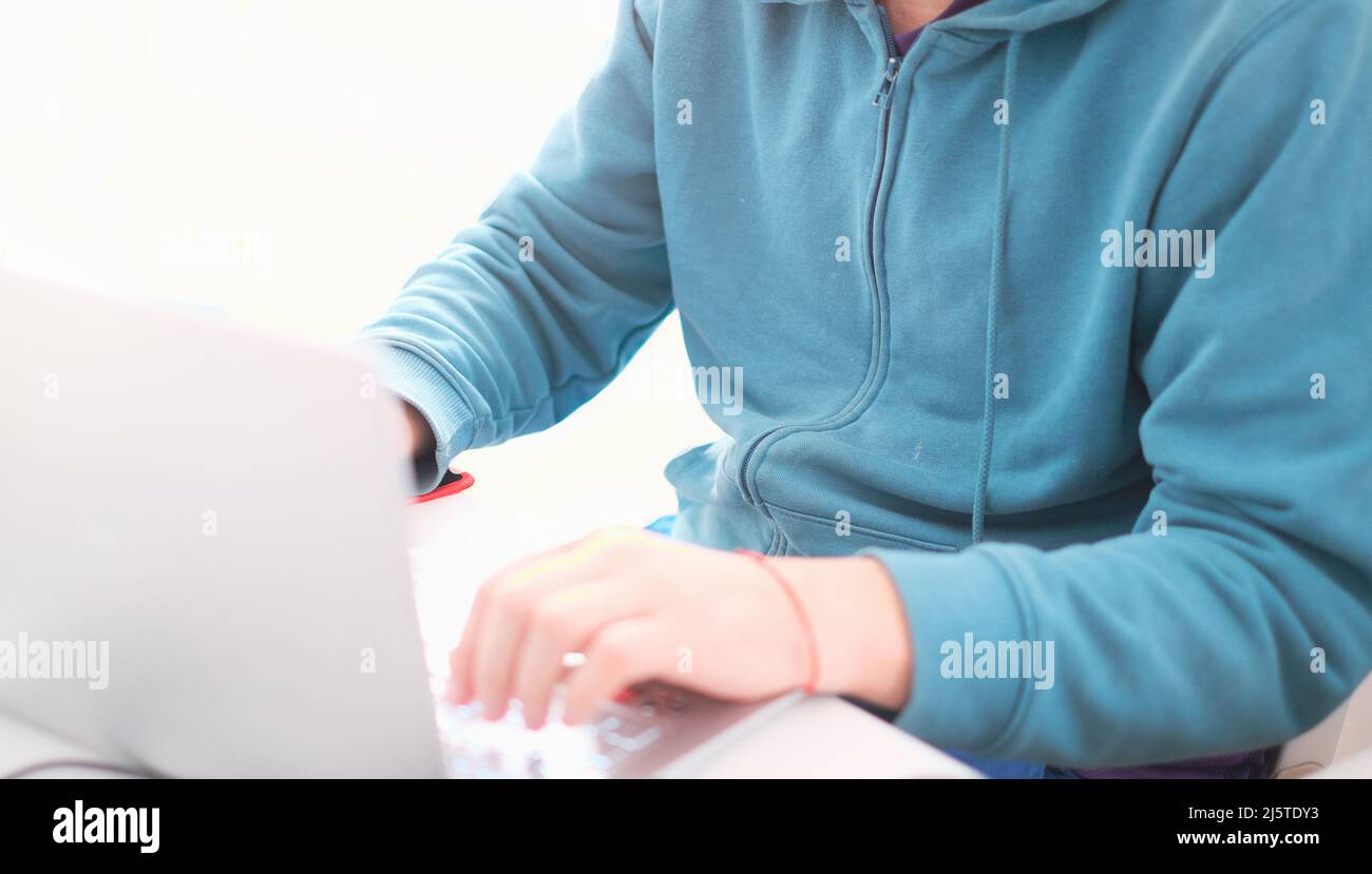 A man in a turquoise sweater in a bright office while working at a ...