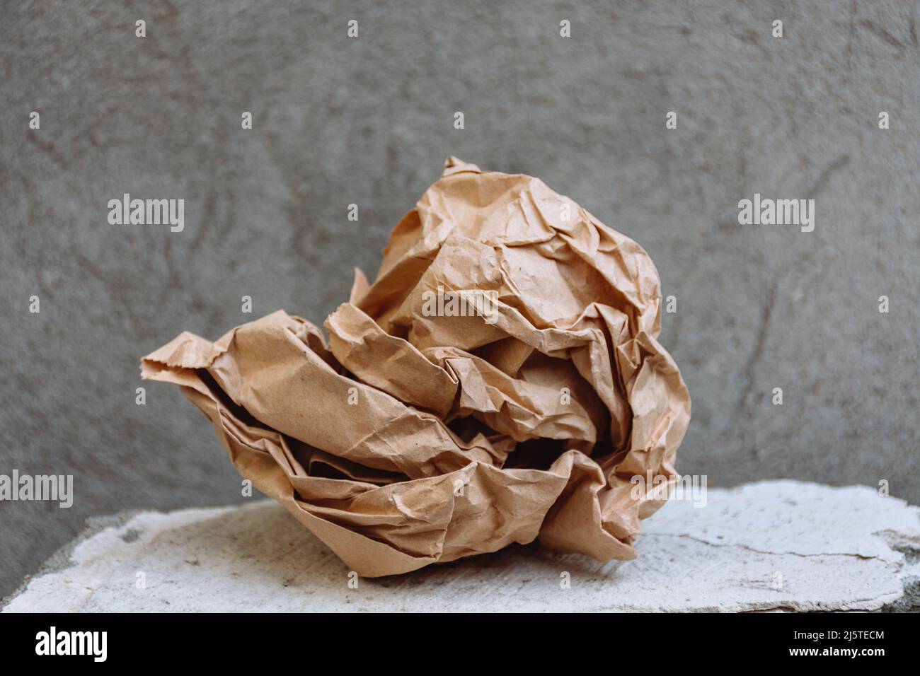 Old kraft paper crumpled into a pile on a stone stand shelf or platform ...