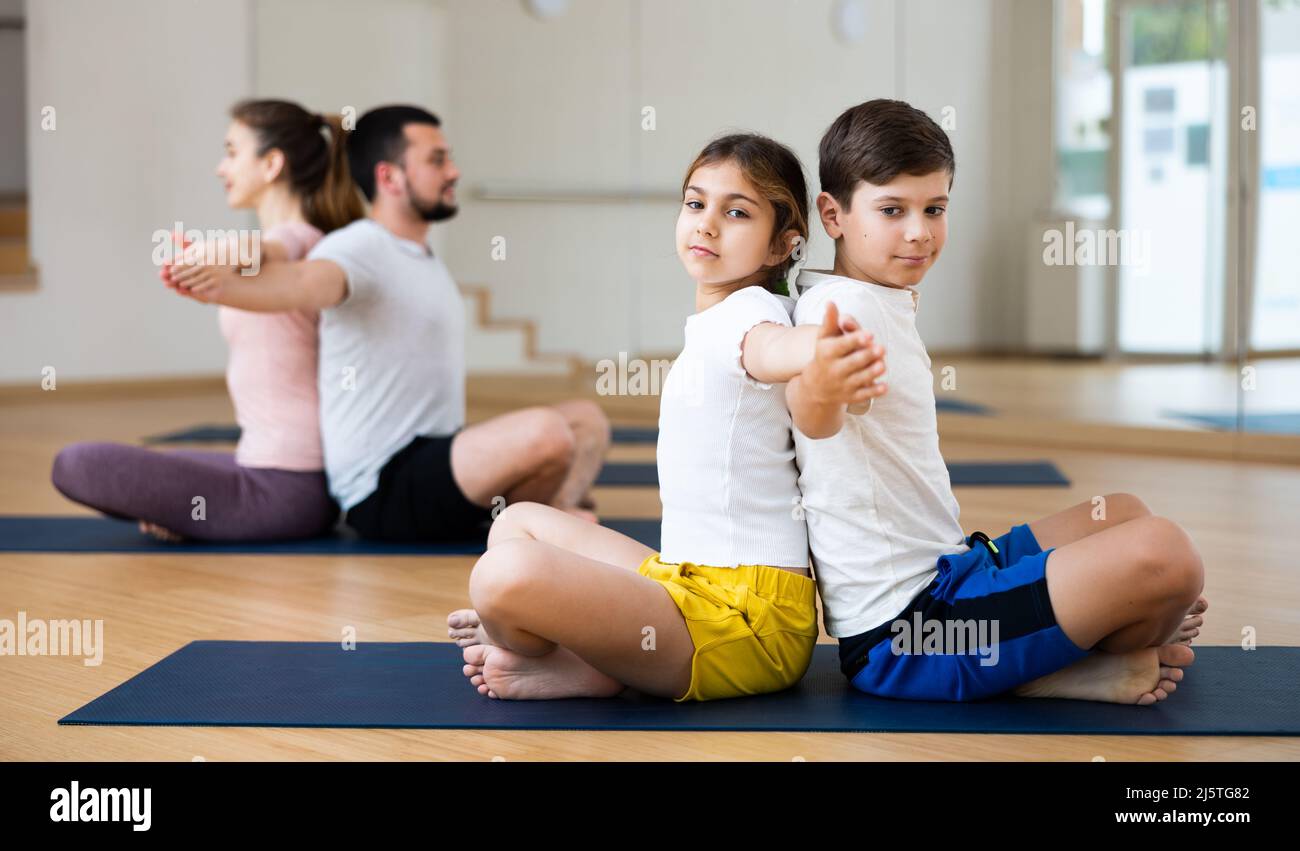Siblings practicing partner yoga poses at gym Stock Photo - Alamy