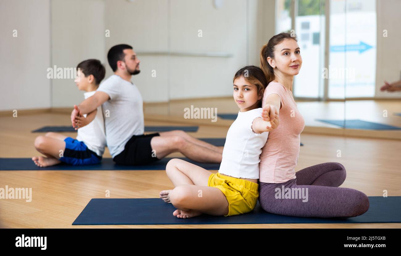 Tween girl with mother doing exercises in pair during family yoga ...