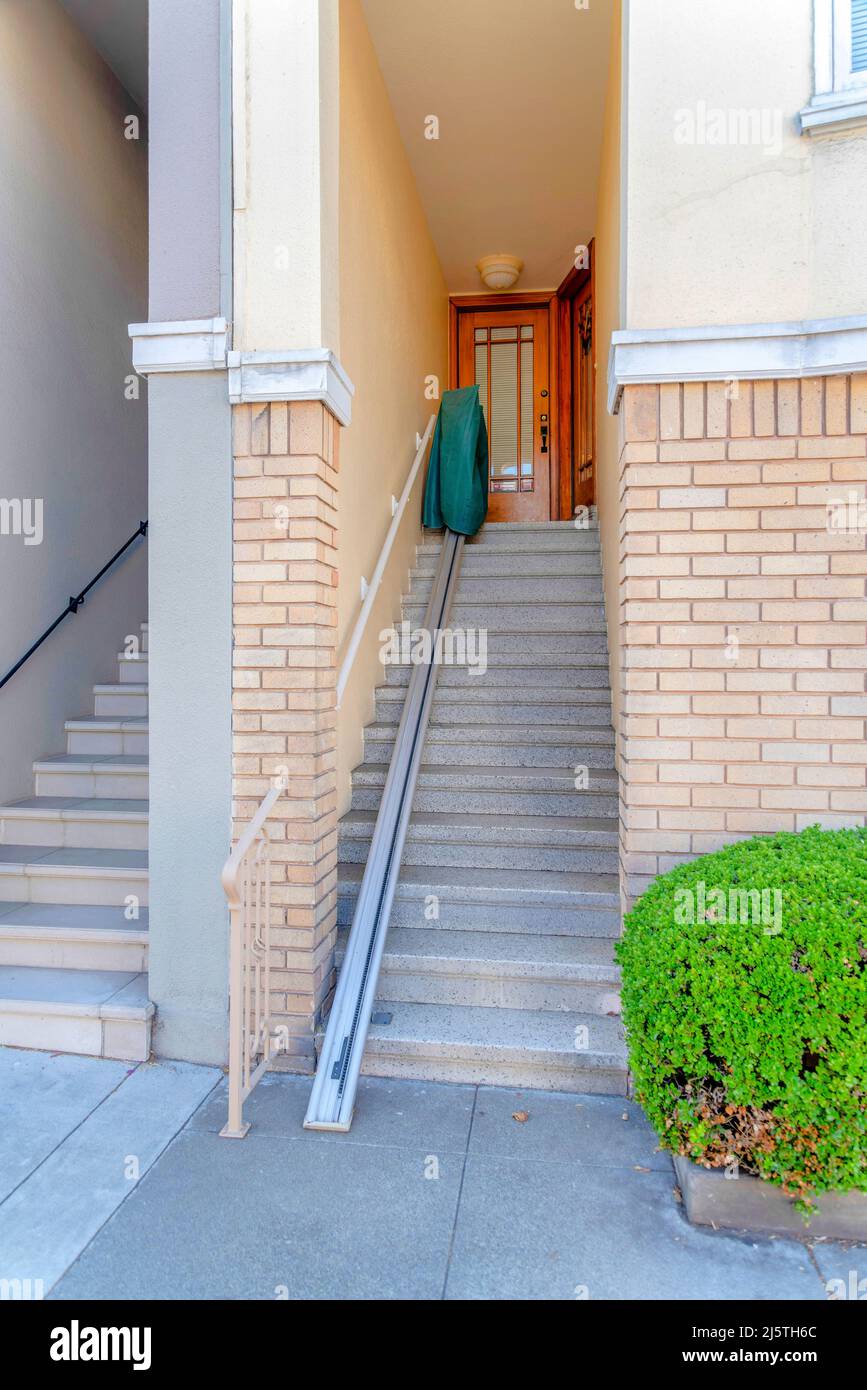 Front entrance of a house with stair lift on a concrete stairs leading ...