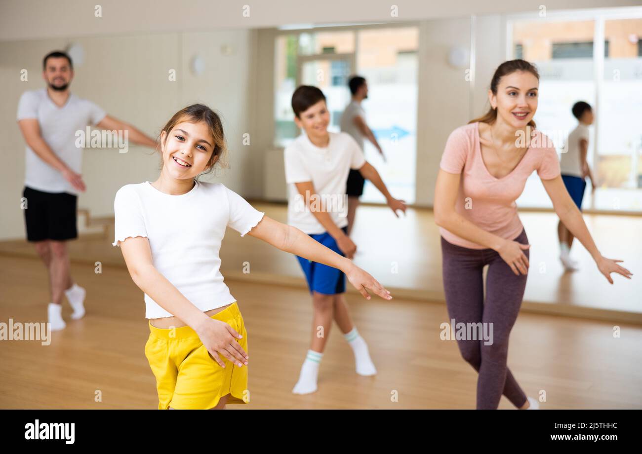 Cheerful teen girl practicing vigorous dance in class with family Stock ...
