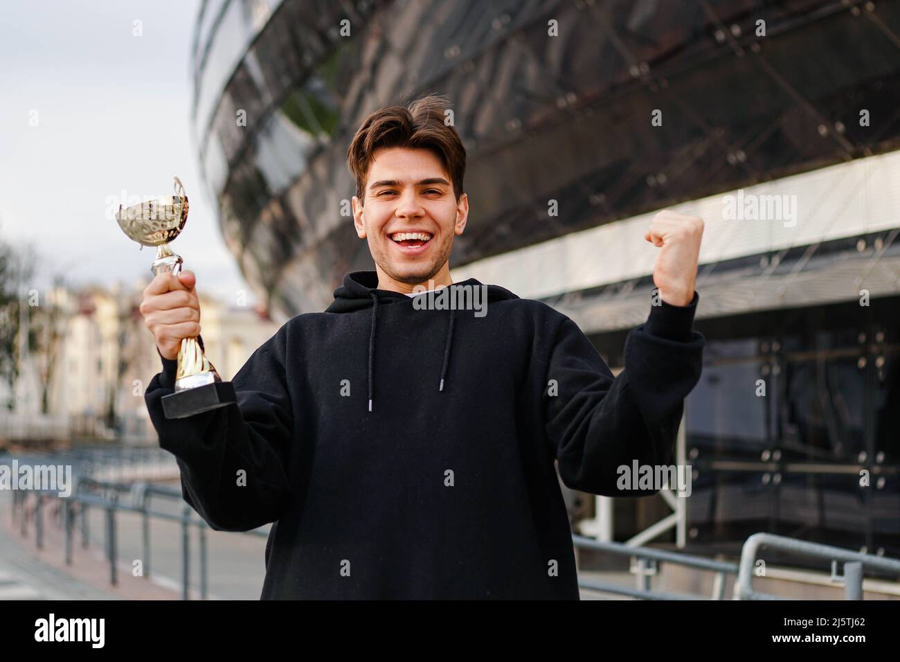 Portrait of young excited sports fan celebrating victory with golden ...