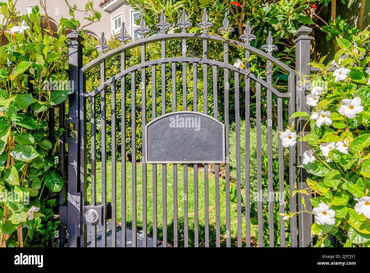 Black wrought iron gate with address number sign and doorbell on the ...