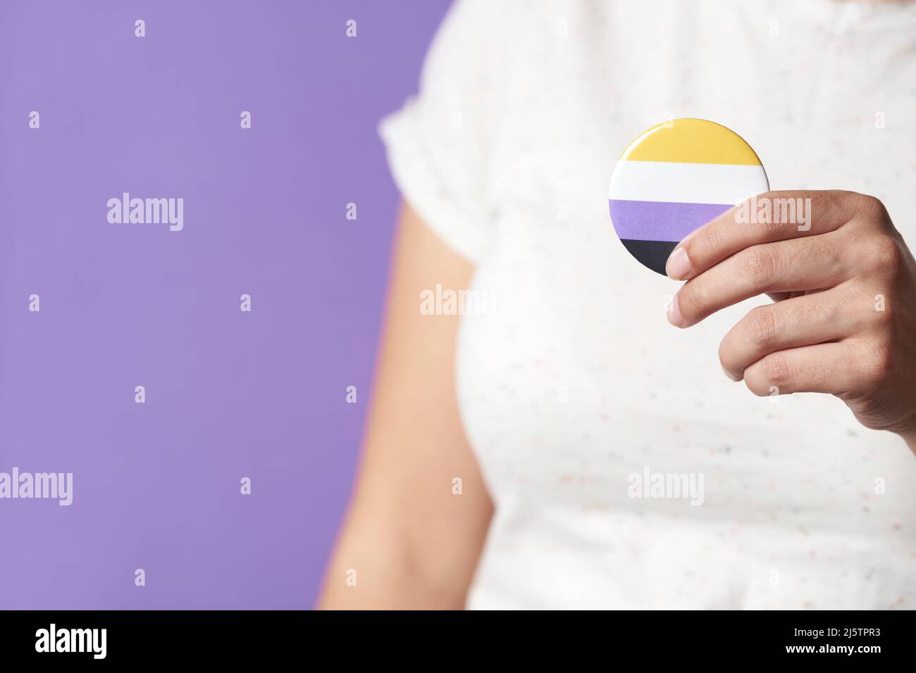 Unrecognizable person holding a non binary flag badge or pin. Concepts ...