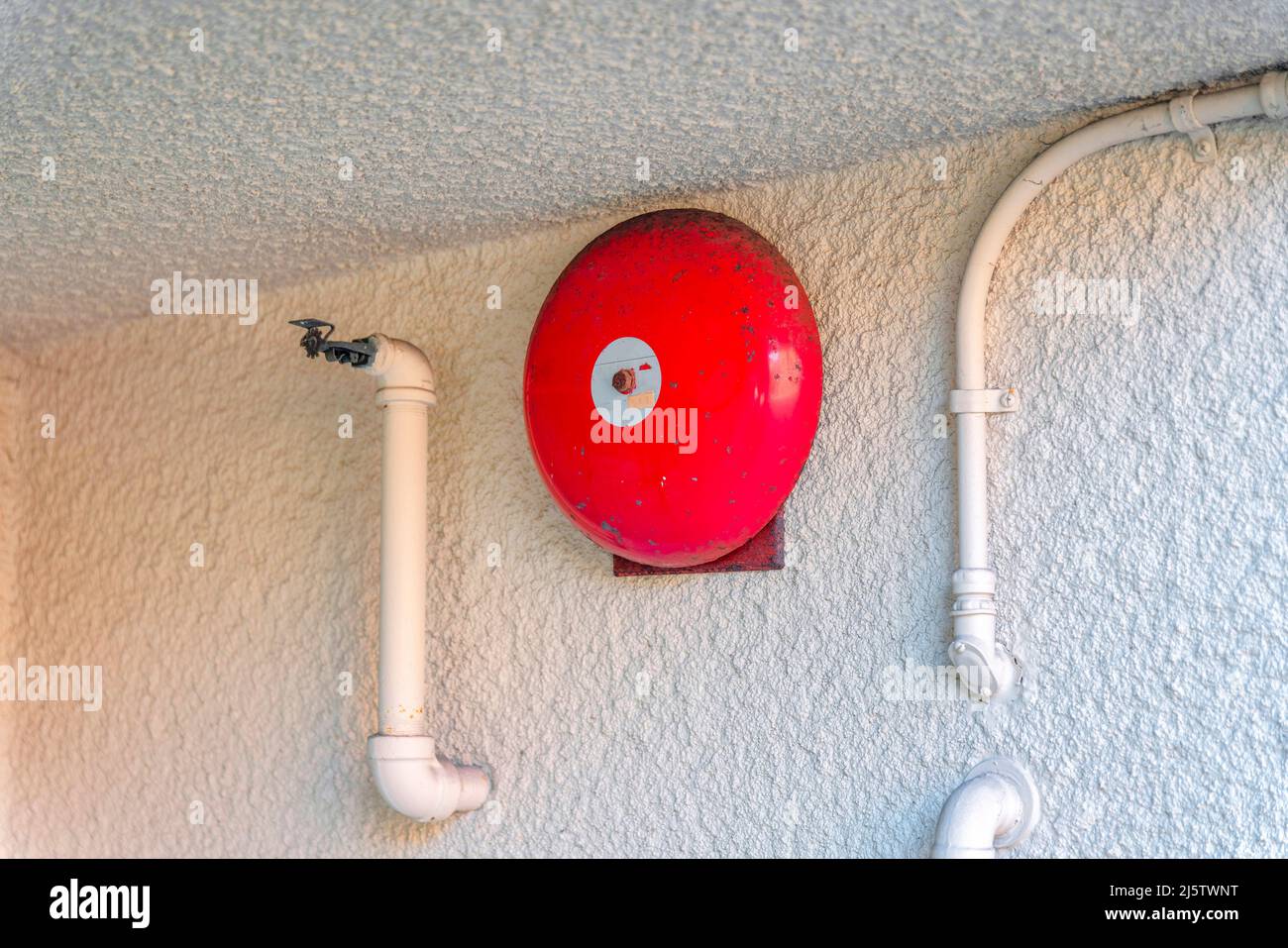 Red fire alarm bell on a painted white textured wall in San Francisco ...