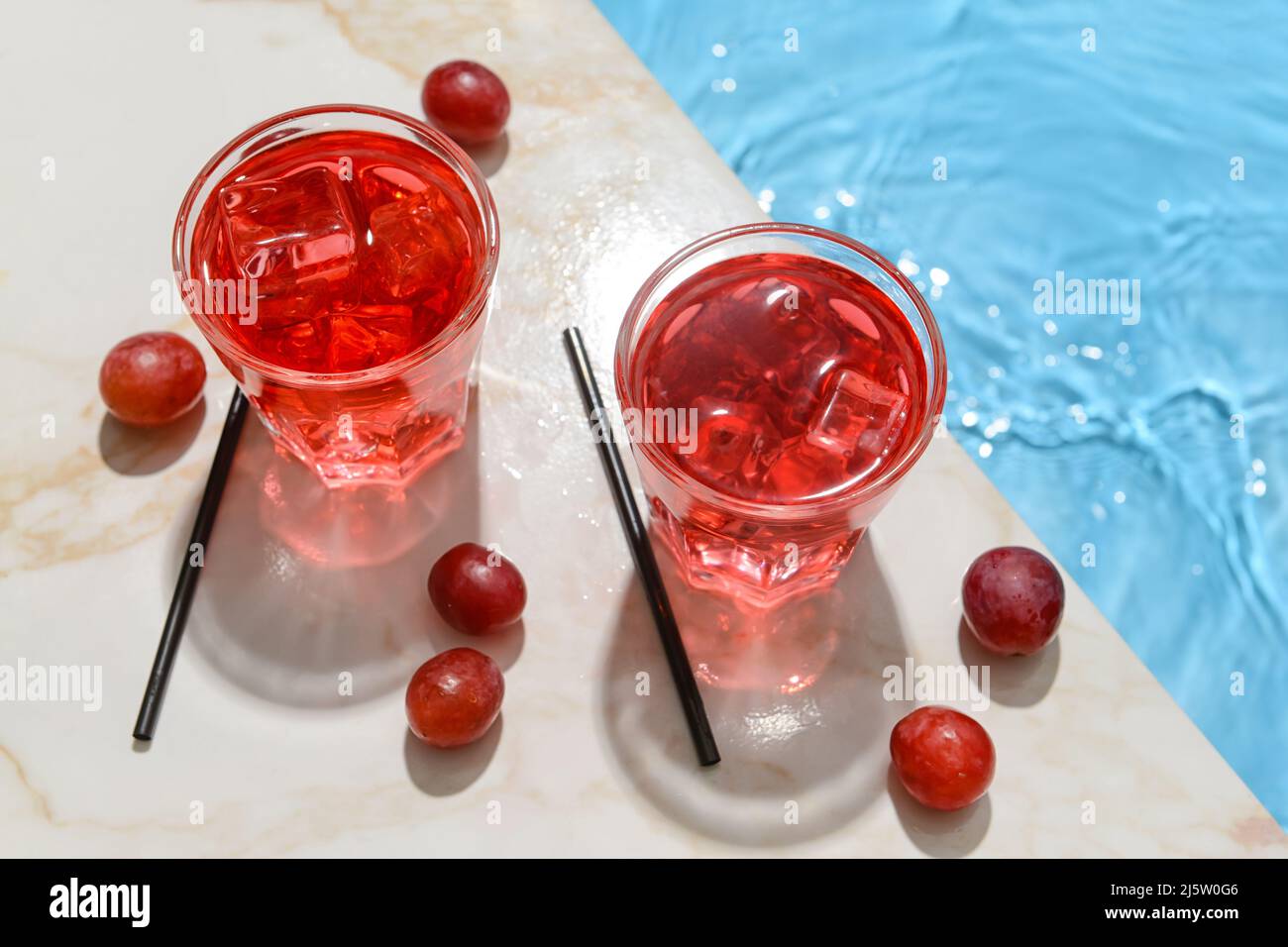 Glasses of fresh grape soda on edge of swimming pool Stock Photo - Alamy