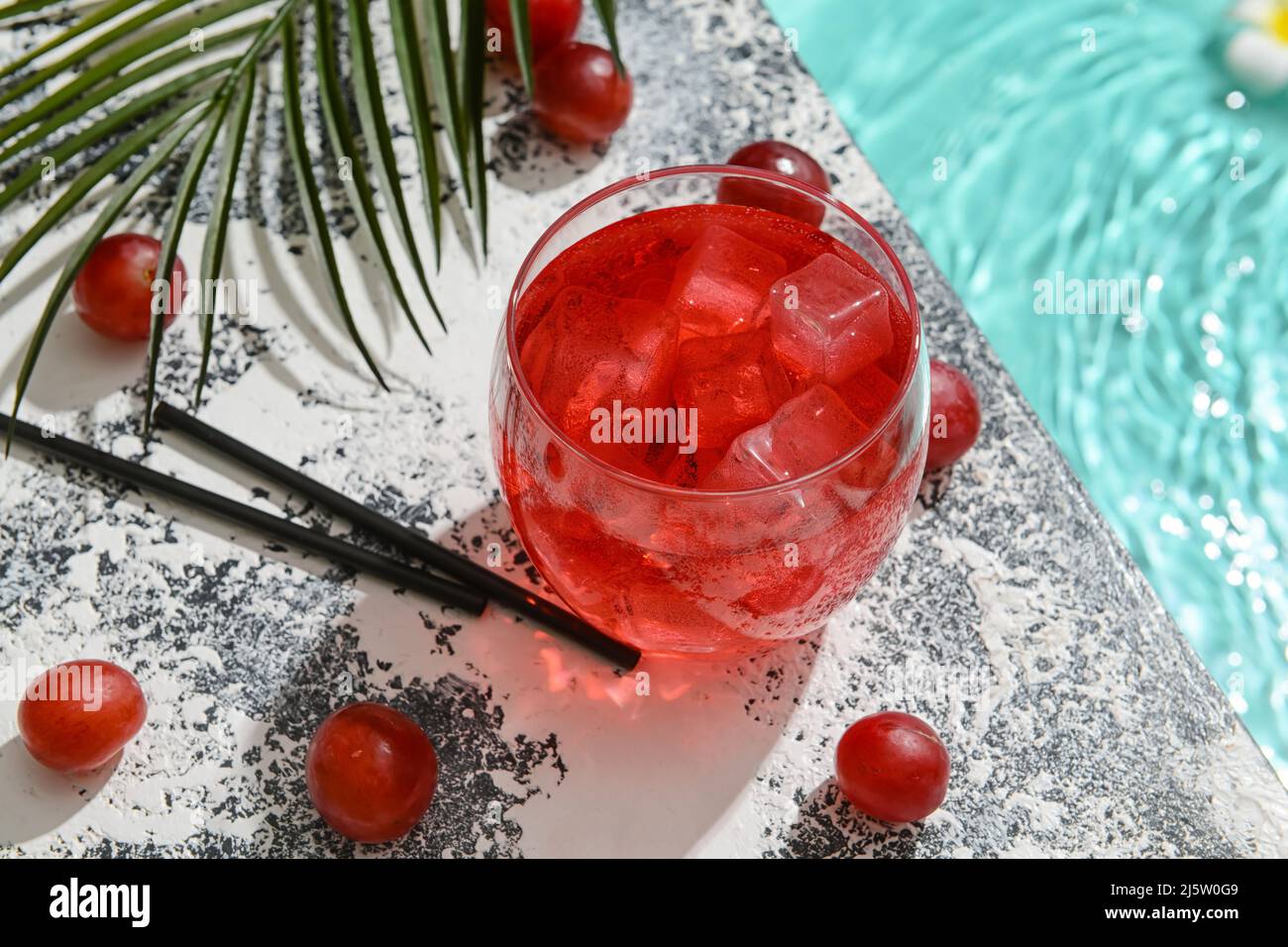 Glass of fresh grape soda on edge of swimming pool, closeup Stock Photo ...