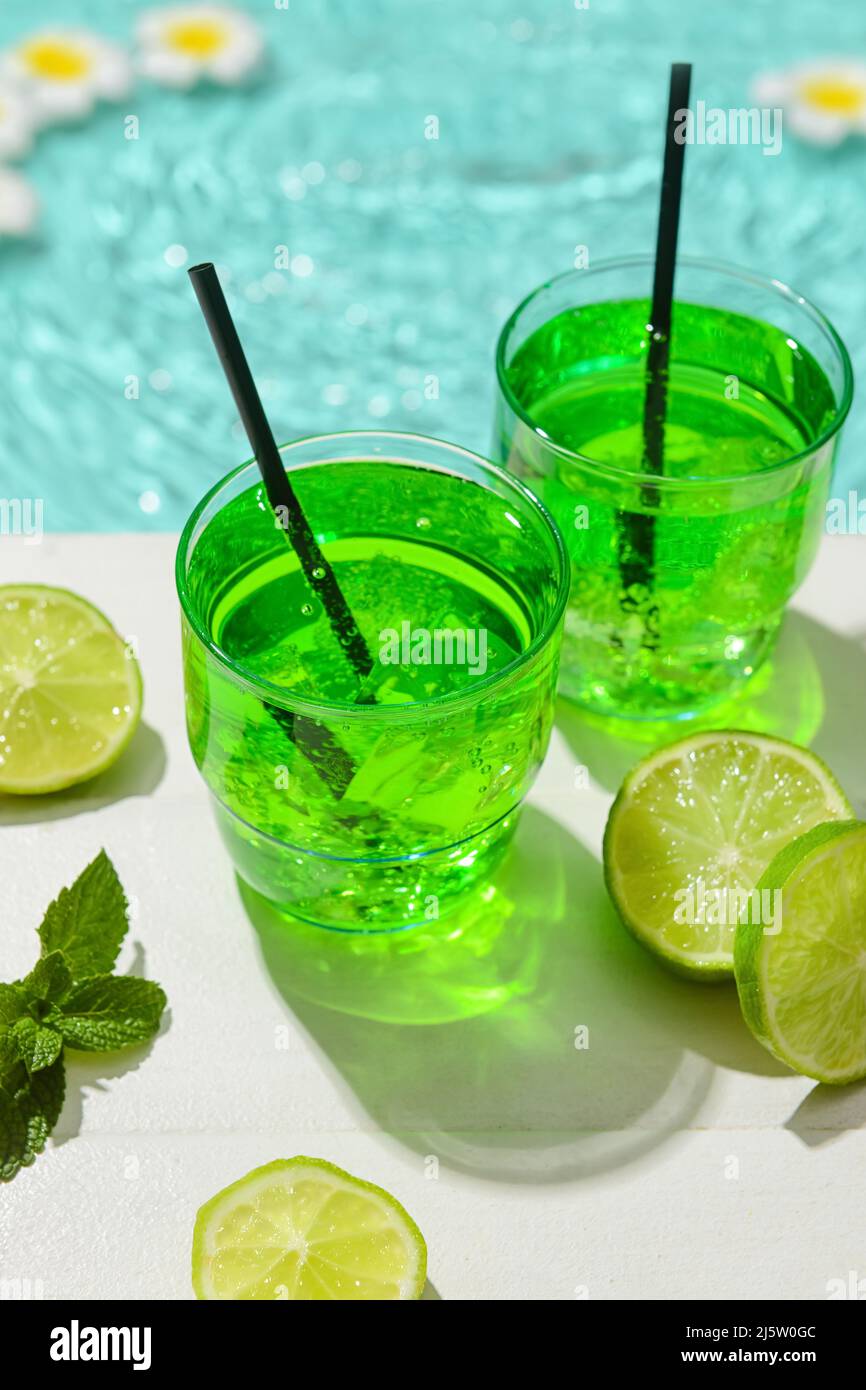 Glasses of fresh lime soda on edge of swimming pool, closeup Stock ...