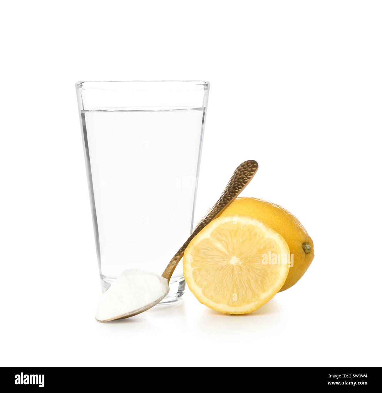 Spoon with baking soda, glass of water and ripe lemons on white ...