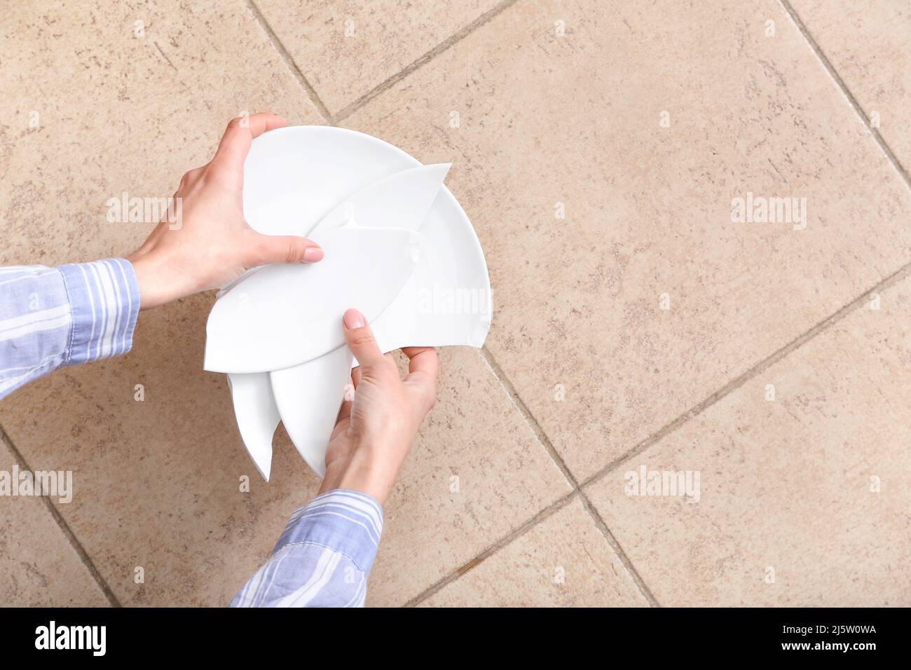 Female hands with pieces of broken plate on color tile Stock Photo - Alamy