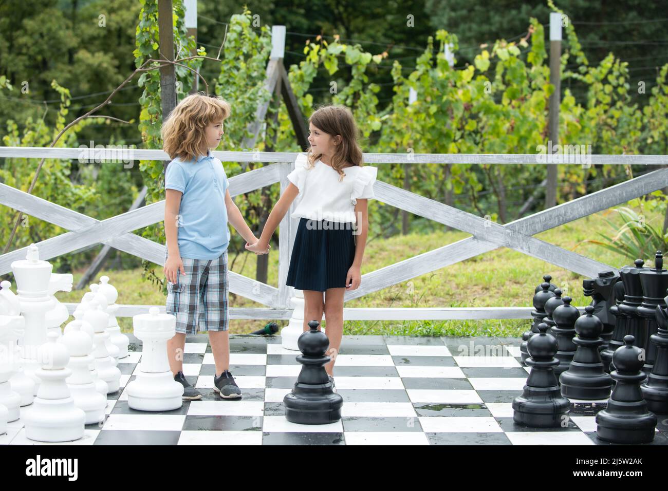 Cute little children playing on big chess board. Portrait of two happy ...