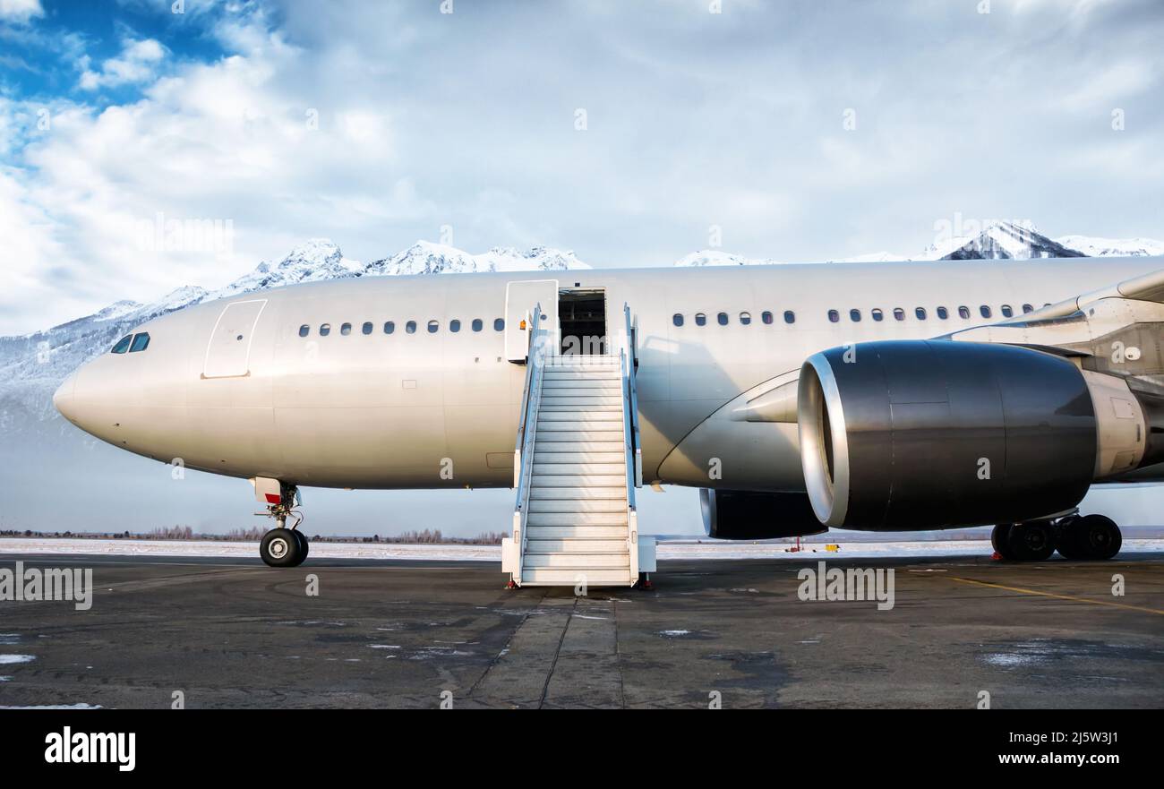Wide body passenger airliner and boarding stairs at the airport apron ...