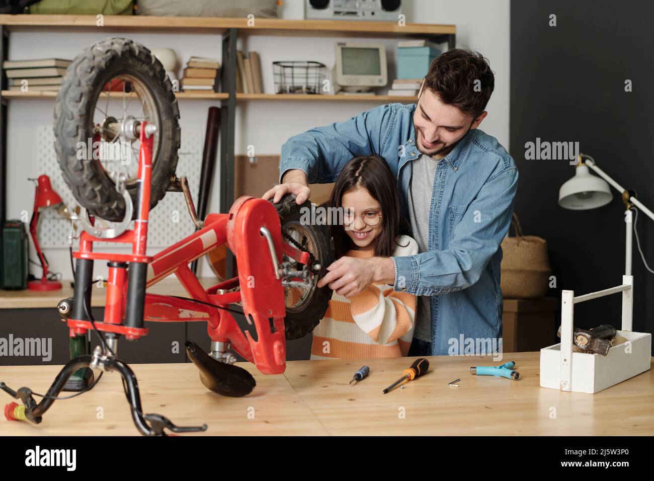 Happy young man and his daughter using wrench to fix part of bicycle ...