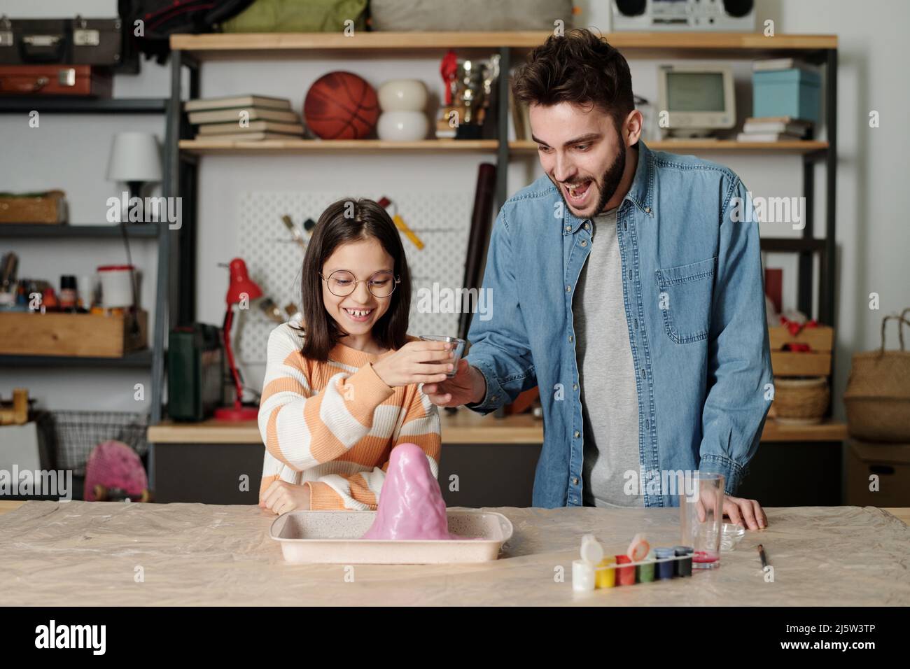 Cute little girl and her father looking at chemical reaction in ...