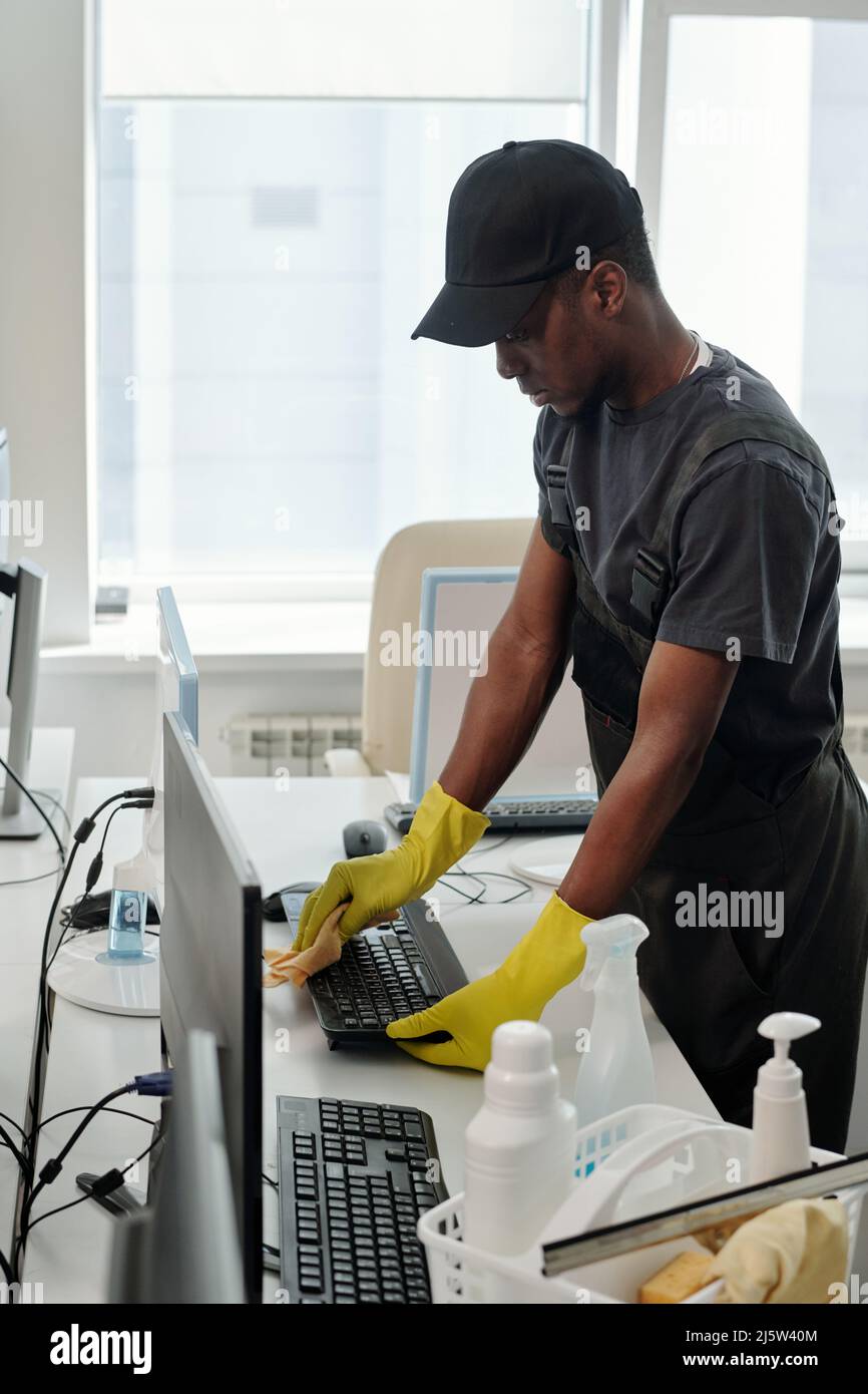 African American male staff of cleaning company in black t-shirt, cap and coveralls and yellow ...
