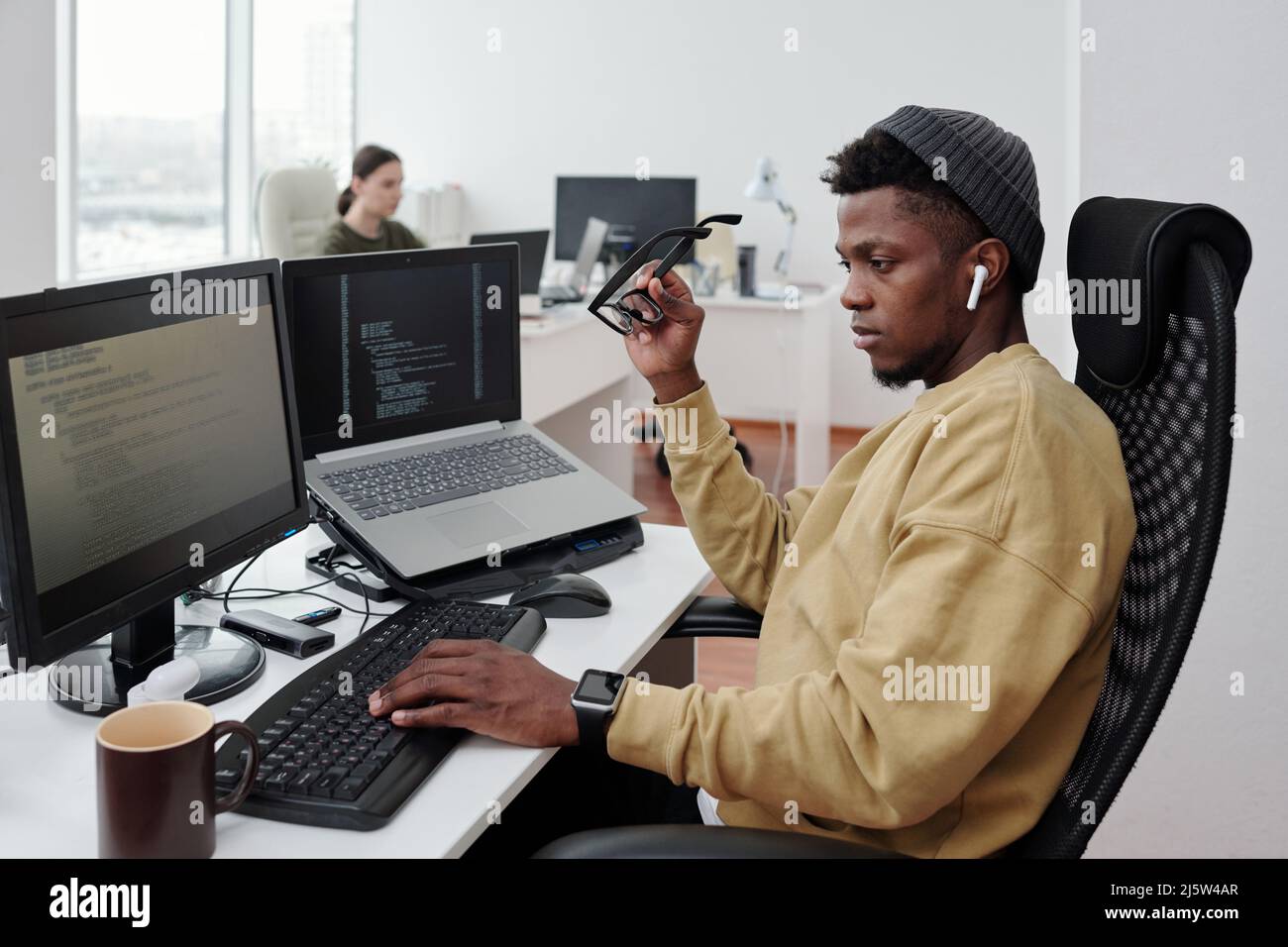 Young contemporary African American it-engineer decoding data by workplace in openspace office ...