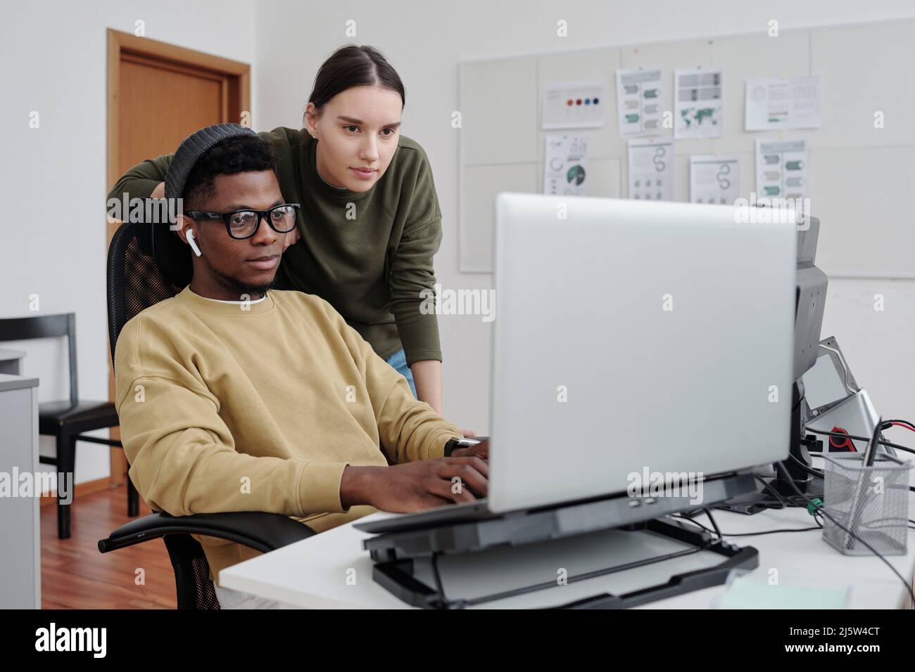 Two contemporary programmers decoding data on laptop screen by ...