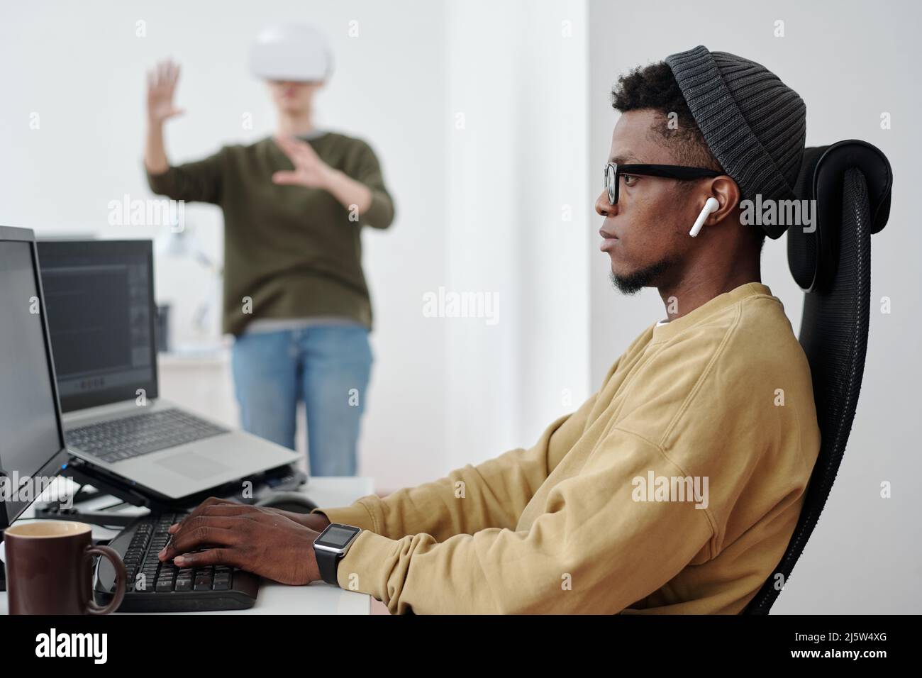 Side view of young serious businessman in earphones, eyeglasses and ...