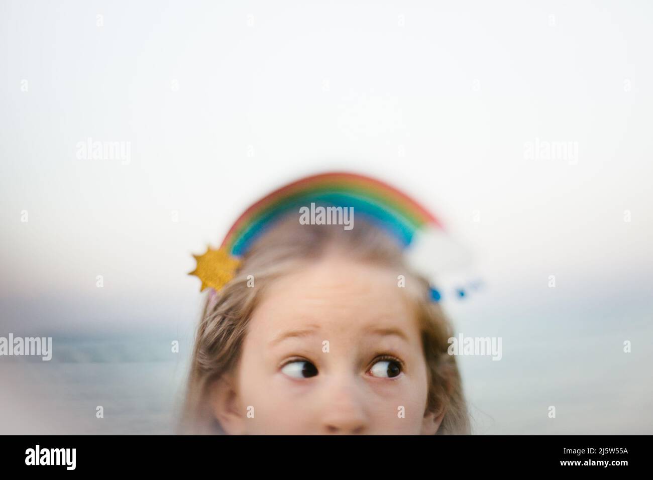 Brown eyed blond seven year old girl half face with rainbow headband ...
