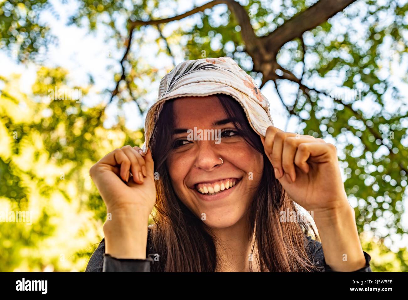 Young playful woman pulling down her hat Stock Photo - Alamy
