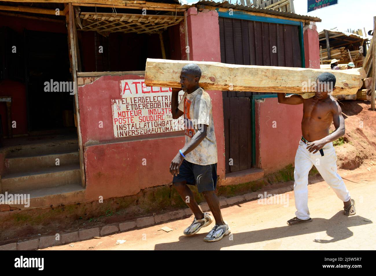 Malagasy men carrying a heavy log of wood in a suburb of Antananarivo ...