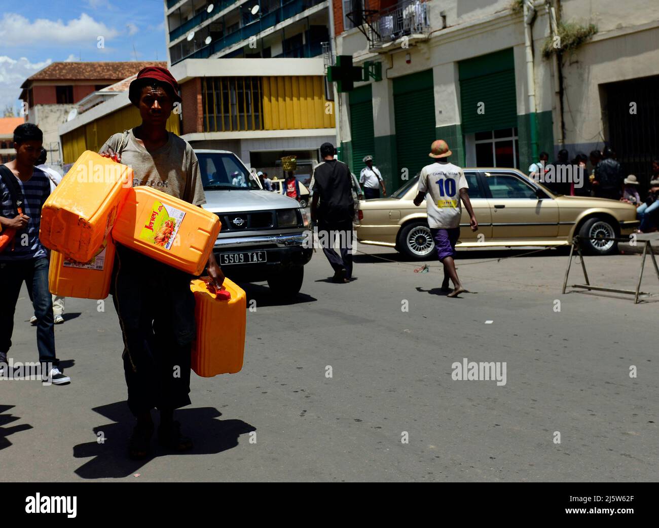 A Malagasy man carrying jerrycans at the market in Antananarivo ...