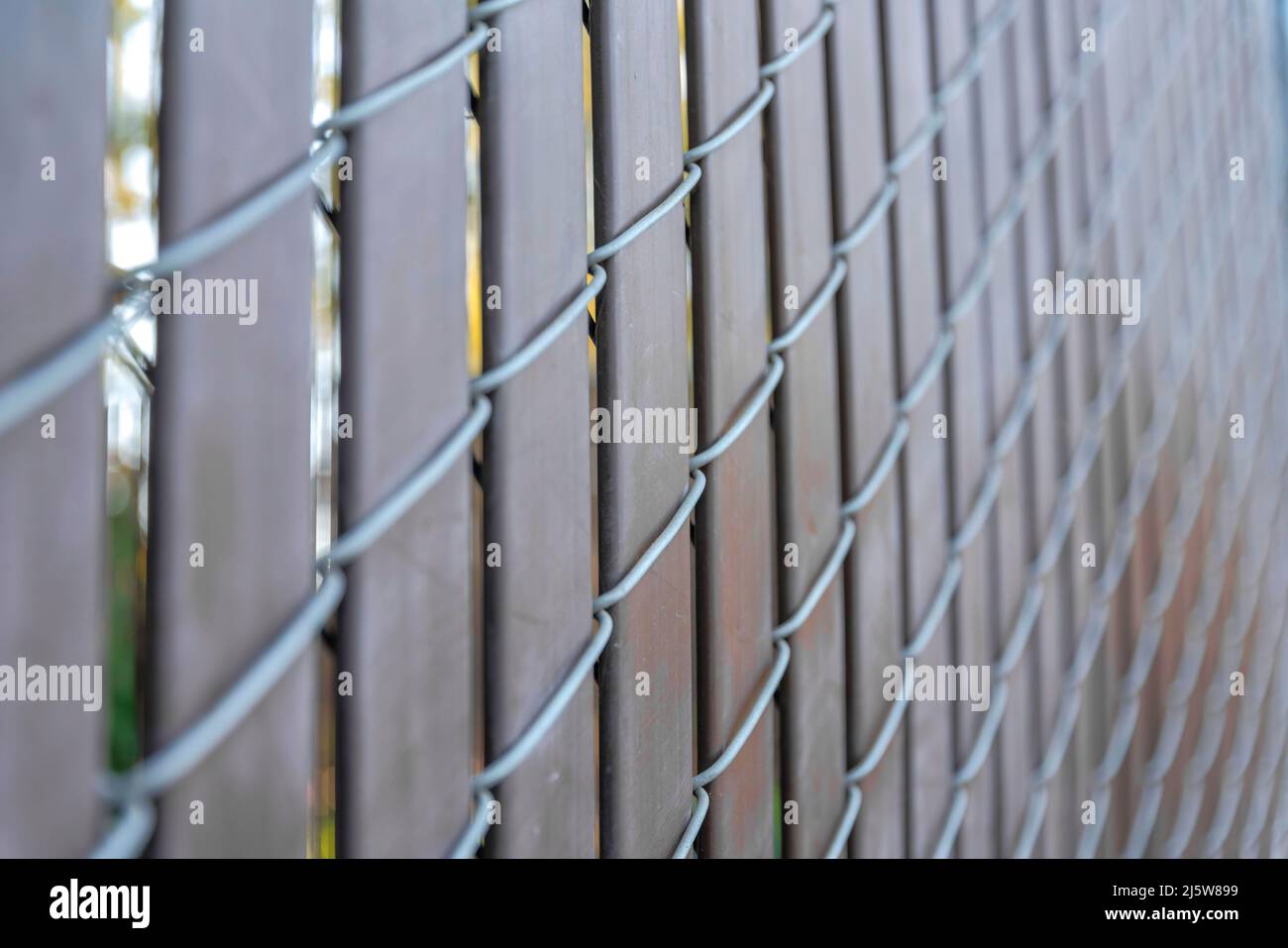 Selective focus of a chain link fence with brown privacy strips at ...