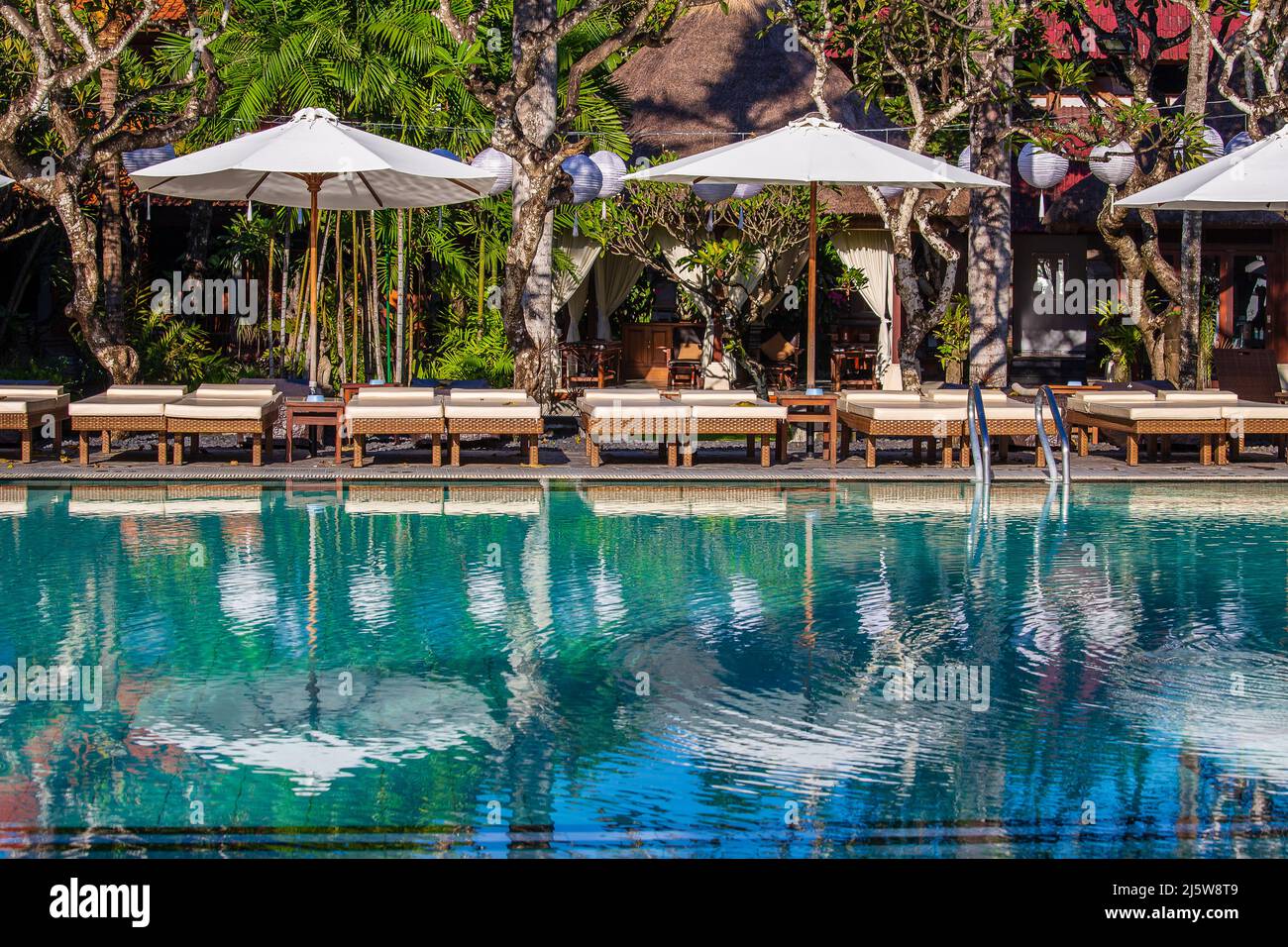 Swimming pool with relaxing beds and sun umbrella in tropical garden in ...