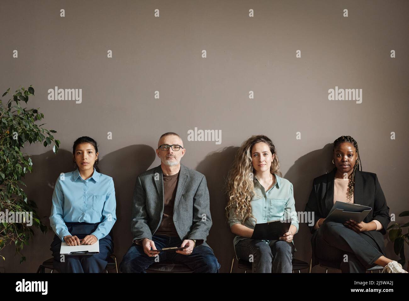 Portrait of multiethnic group of candidates sitting on chairs in ...