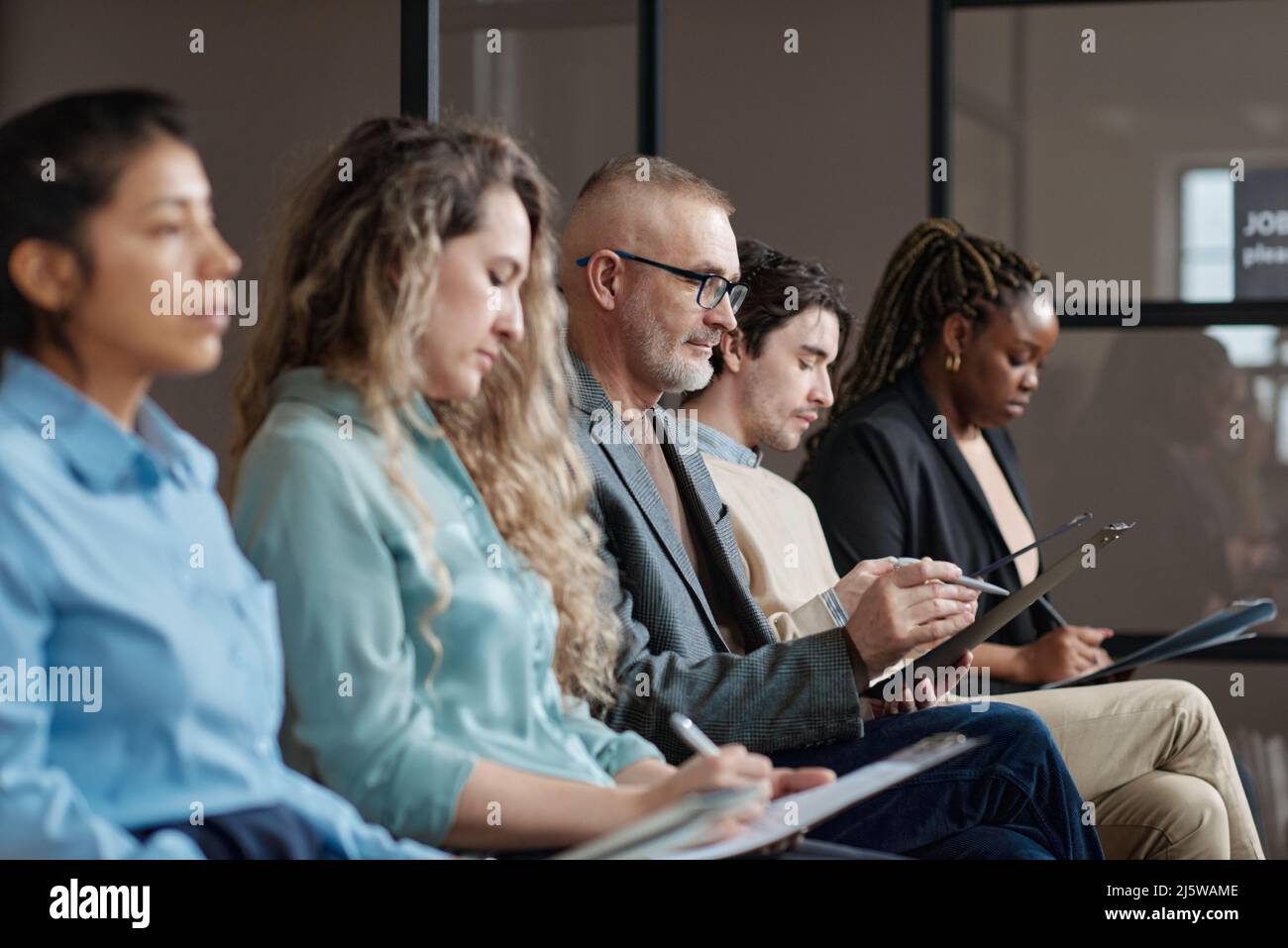 Mature man in eyeglasses filling the form before job interview while ...