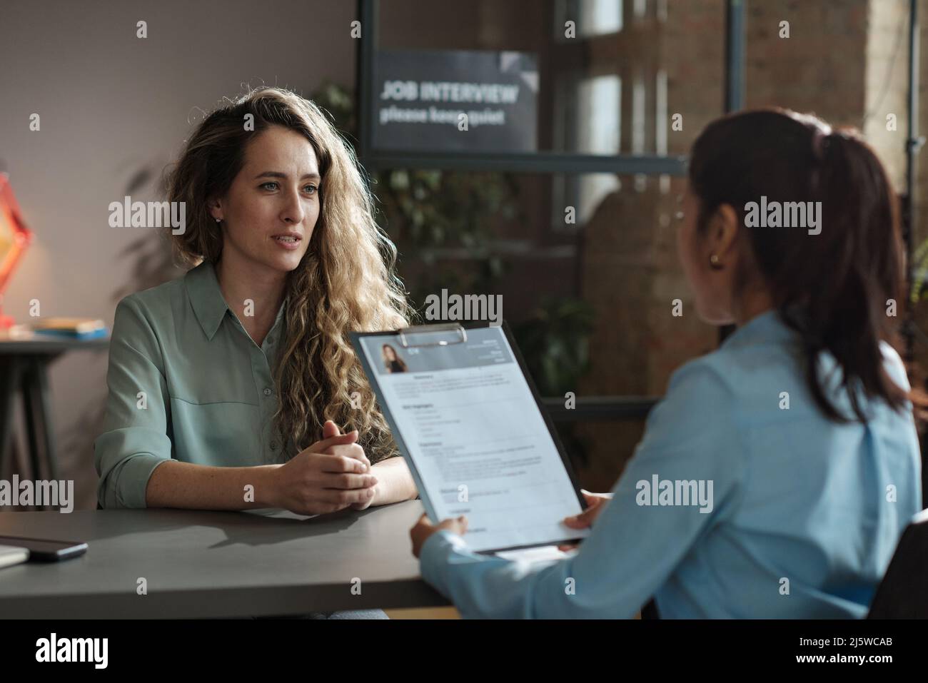 Young woman telling about her work experience while manager examining ...