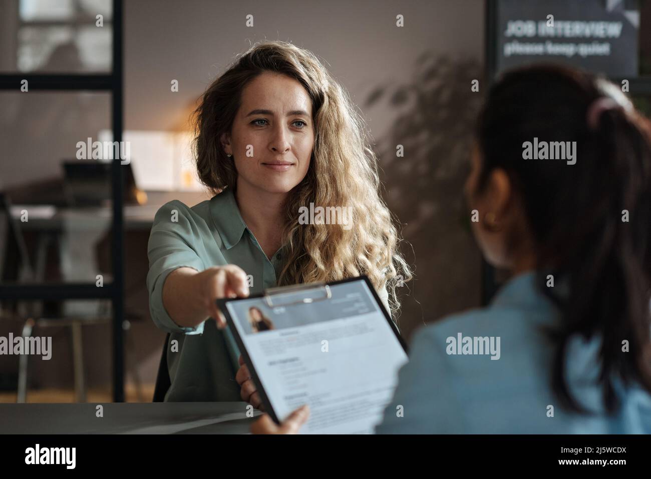 Young female candidate giving her resume to interviewer during job ...