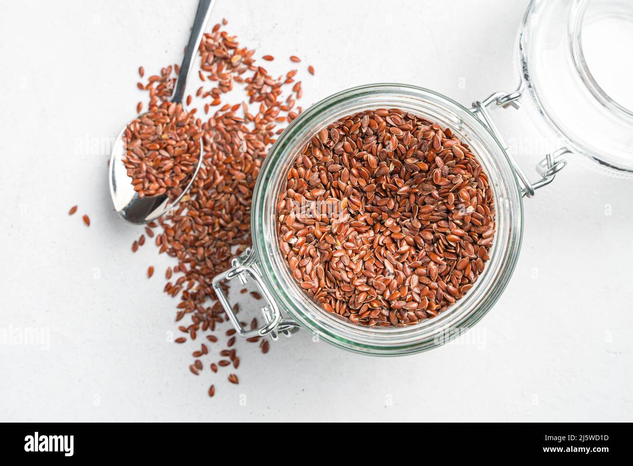 Flax seeds with a transparent jar with a spoon on a gray background ...